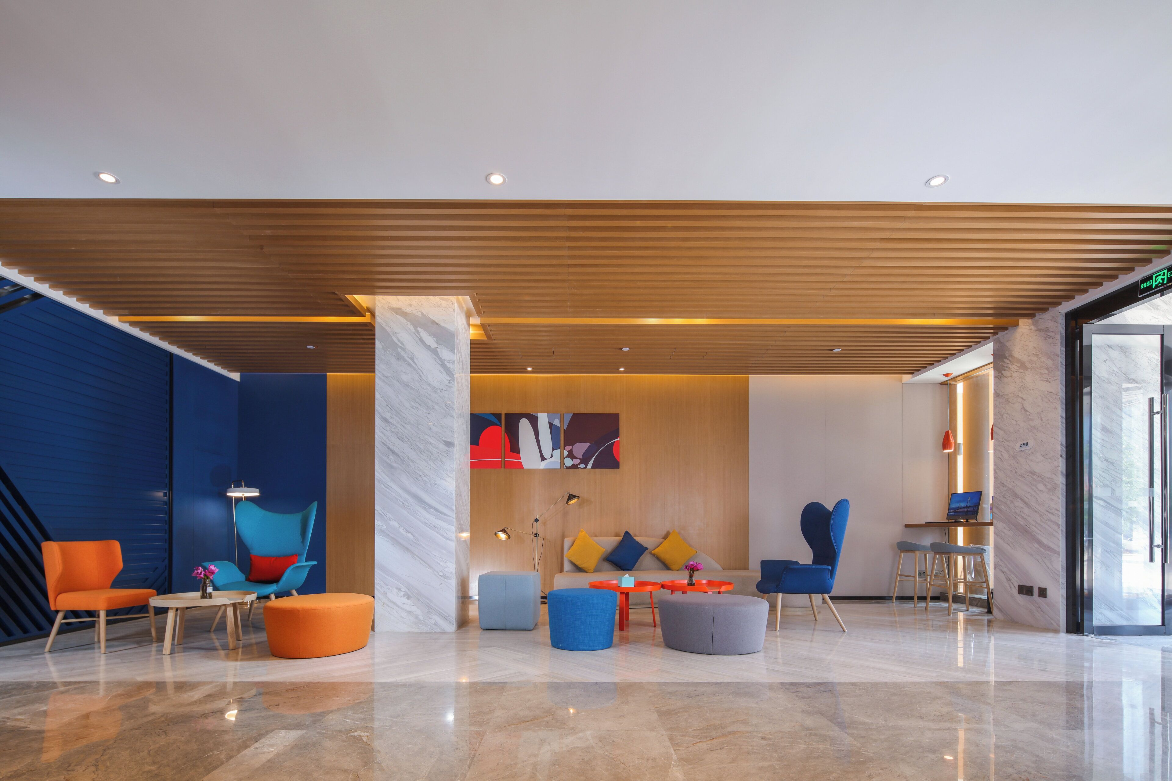 Um hall moderno com piso de mármore, teto de madeira e composições de assentos coloridas.