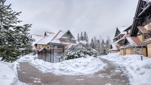 Uma trilha coberta de neve que leva a um edifício com fachada de tijolos e cerca de metal.