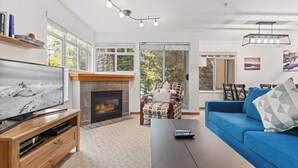 Uma sala de estar moderna com lareira, um sofá azul, uma televisão e uma mesa de centro.