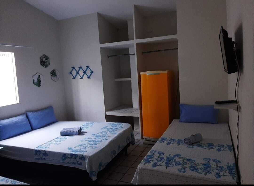 Quarto com duas camas, um guarda-roupa e uma televisão.