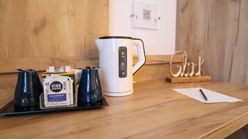 Uma estação de café com uma cafeteira branca, um suporte com cápsulas de café e uma placa de madeira com a inscrição 'Glück'.