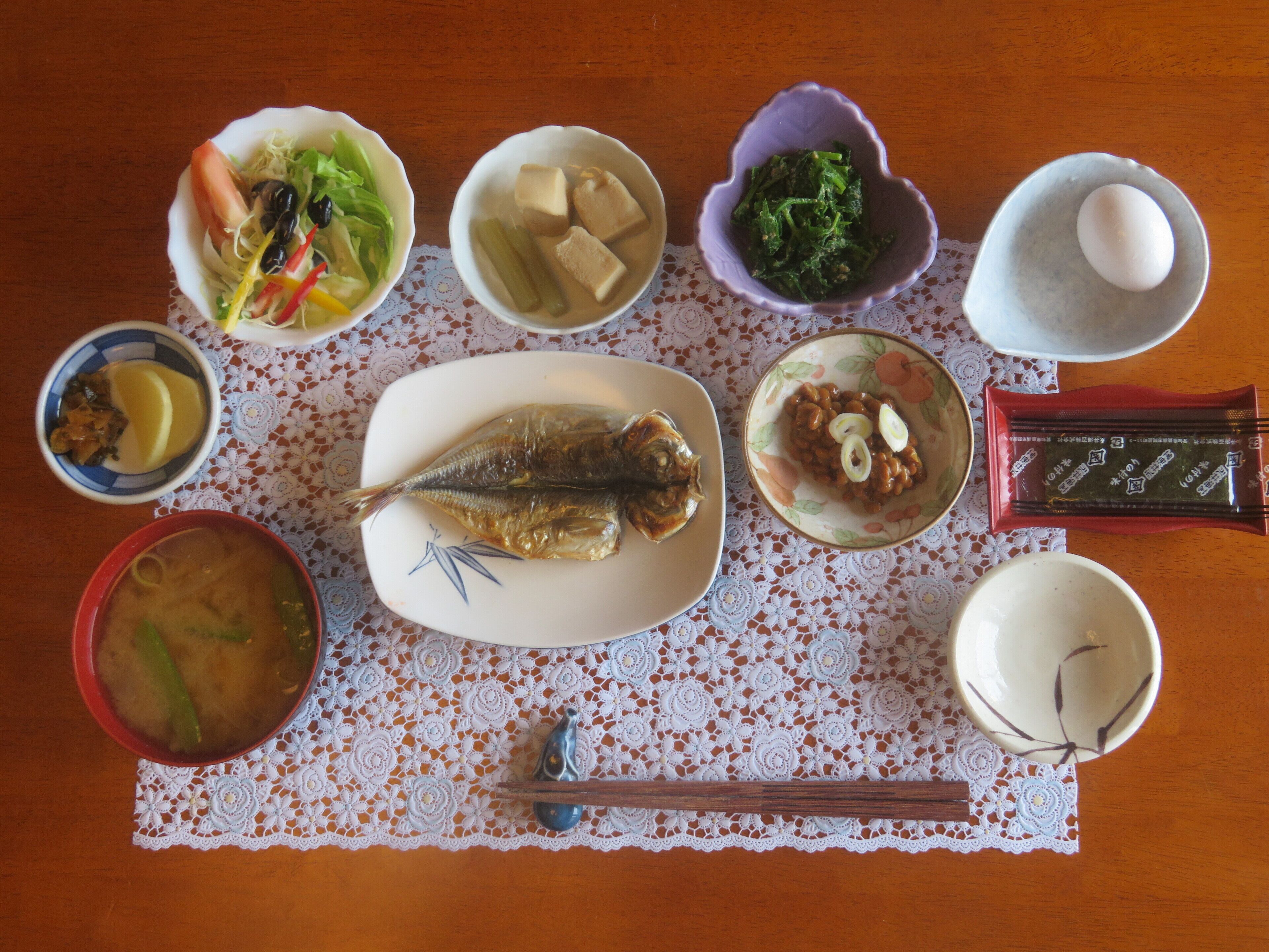 Uma mesa com diversos pratos, incluindo peixe, legumes e uma tigela de sopa.