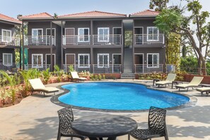 Um hotel com vários andares, varandas, piscina e área de estar ao ar livre.