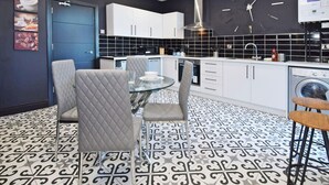 Uma cozinha moderna com armários brancos, painel de fundo preto e piso estampado.