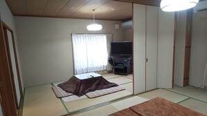 Quarto japonês tradicional com tatame, futon, televisão e porta deslizante.