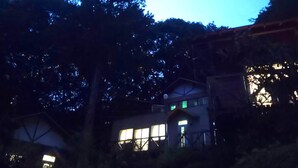 Uma casa com varanda aparente e uma grande árvore ao fundo.