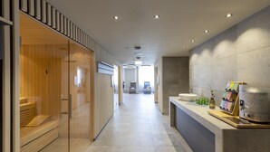 Corredor moderno de hotel com área de recepção, espaço de estar e vista para um quarto.