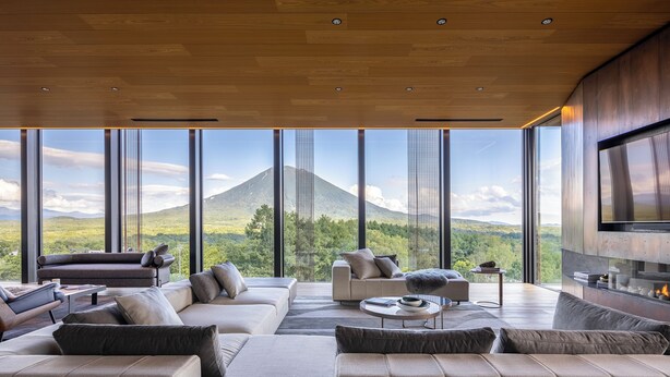 Uma sala de estar moderna com grandes janelas, lareira e vista para uma montanha.