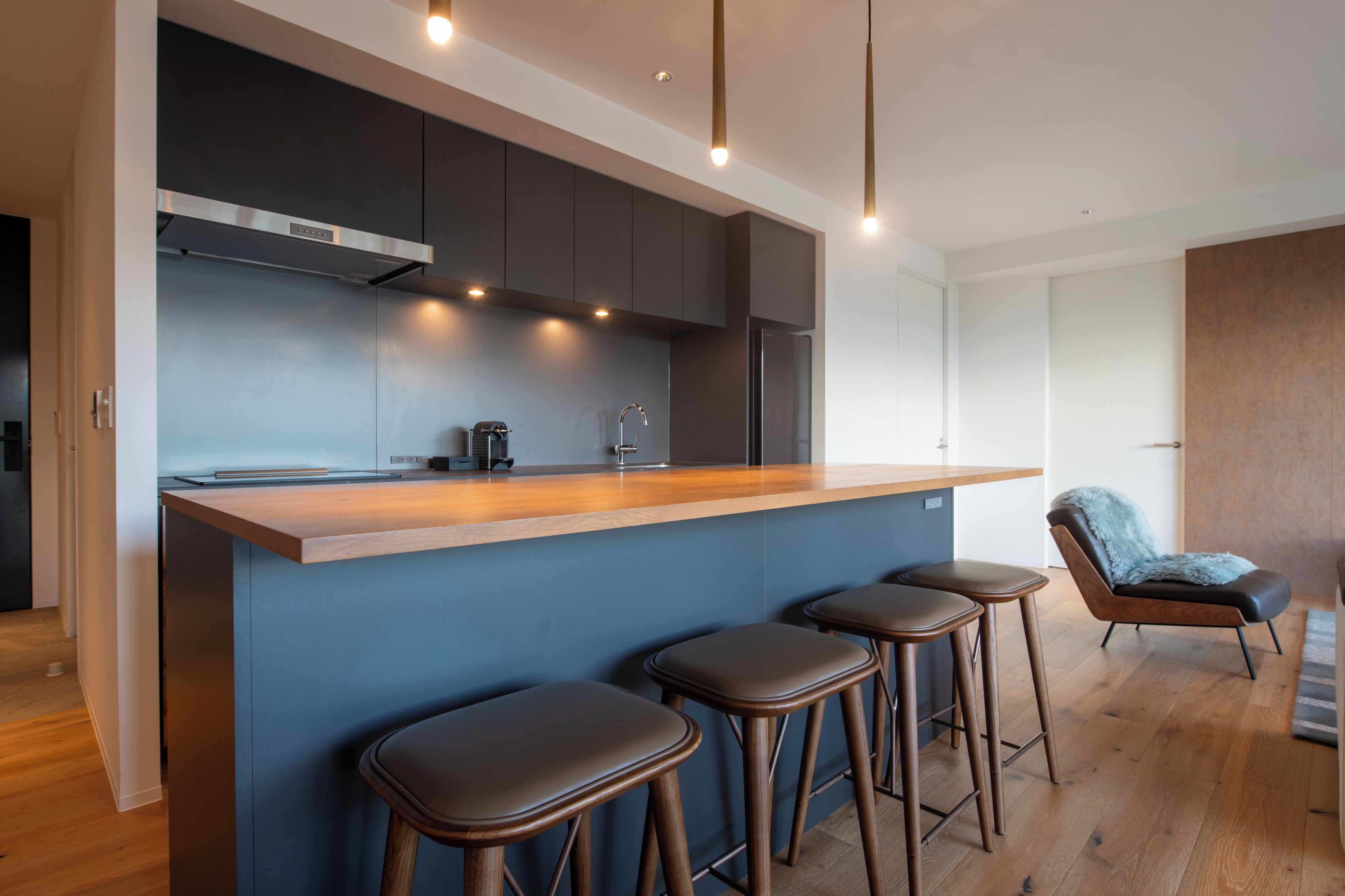 Cozinha moderna com área de bar, banquetes de madeira e parede azul de destaque.