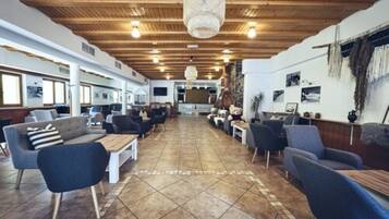 Um hall amplo com móveis modernos, teto de madeira e um lustre central.