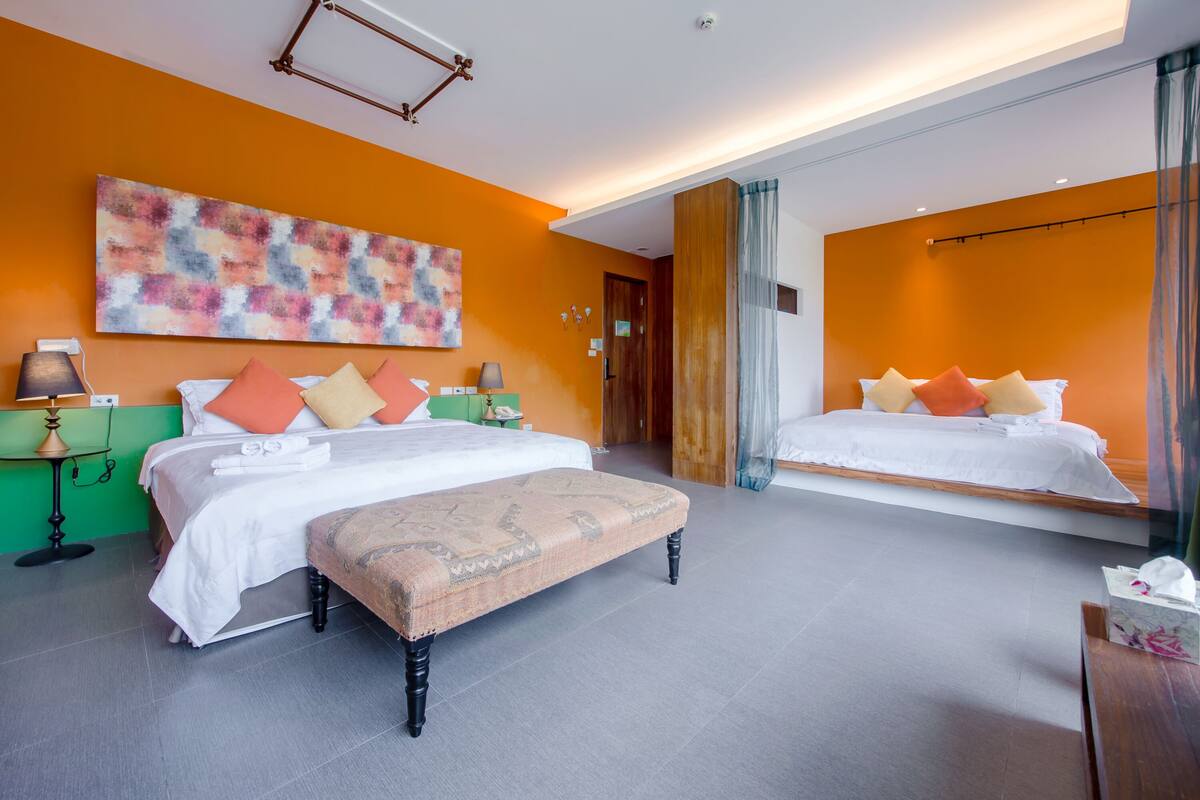 Quarto de hotel moderno com duas camas, uma pintura abstrata grande e vista através de uma porta de vidro.