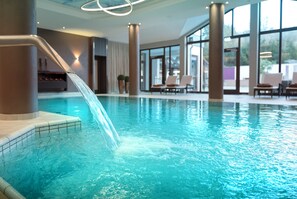 Piscina interna com escorregador, amplas janelas e design de interiores moderno.