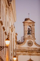 Um edifício histórico com uma torre de sino, um relógio e um ninho no telhado.