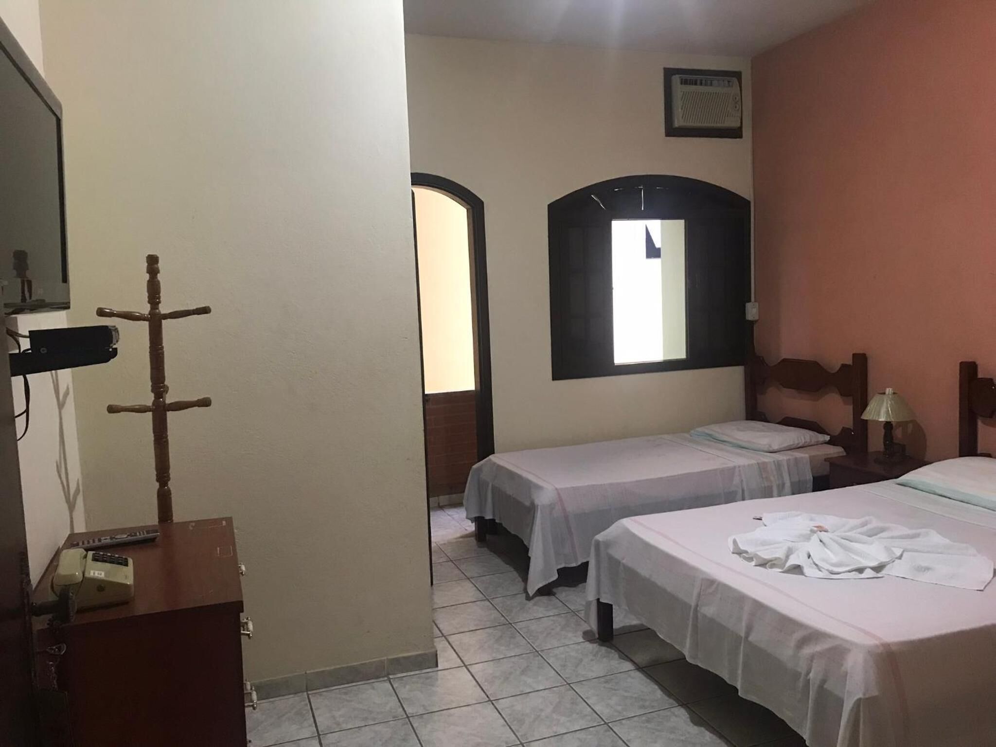 Quarto com duas camas, uma escrivaninha com telefone e janela com vista.