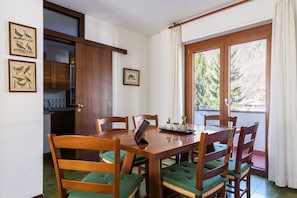 Uma sala de jantar com mesa e cadeiras de madeira, um tablet sobre a mesa, e quadros nas paredes.