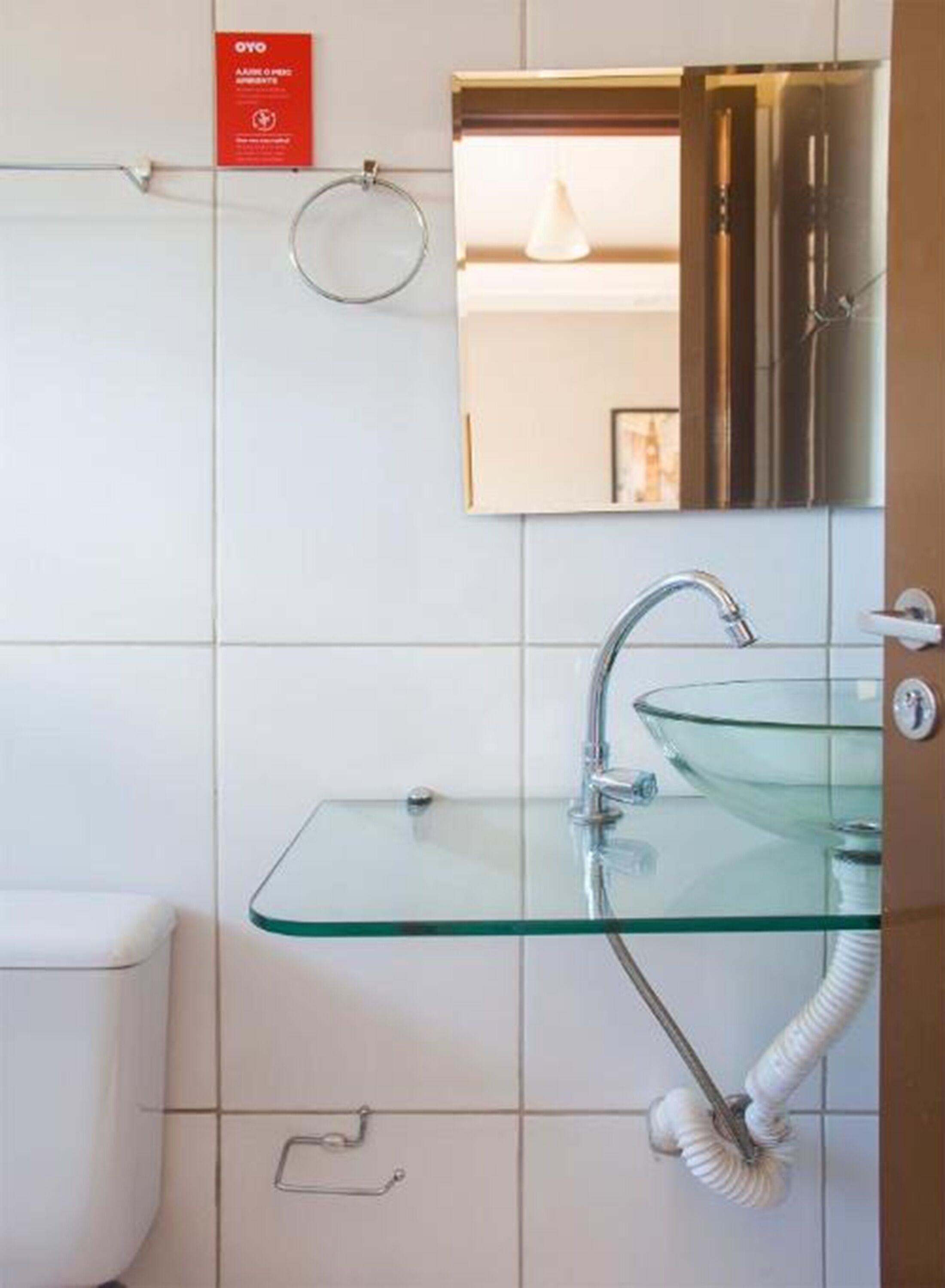 Casa de banho moderna com lavatório de vidro, sanita e suporte para toalhas.