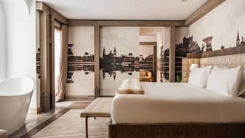 Quarto de hotel moderno com uma cama grande, um espaço de estar e vista para um mural urbano.