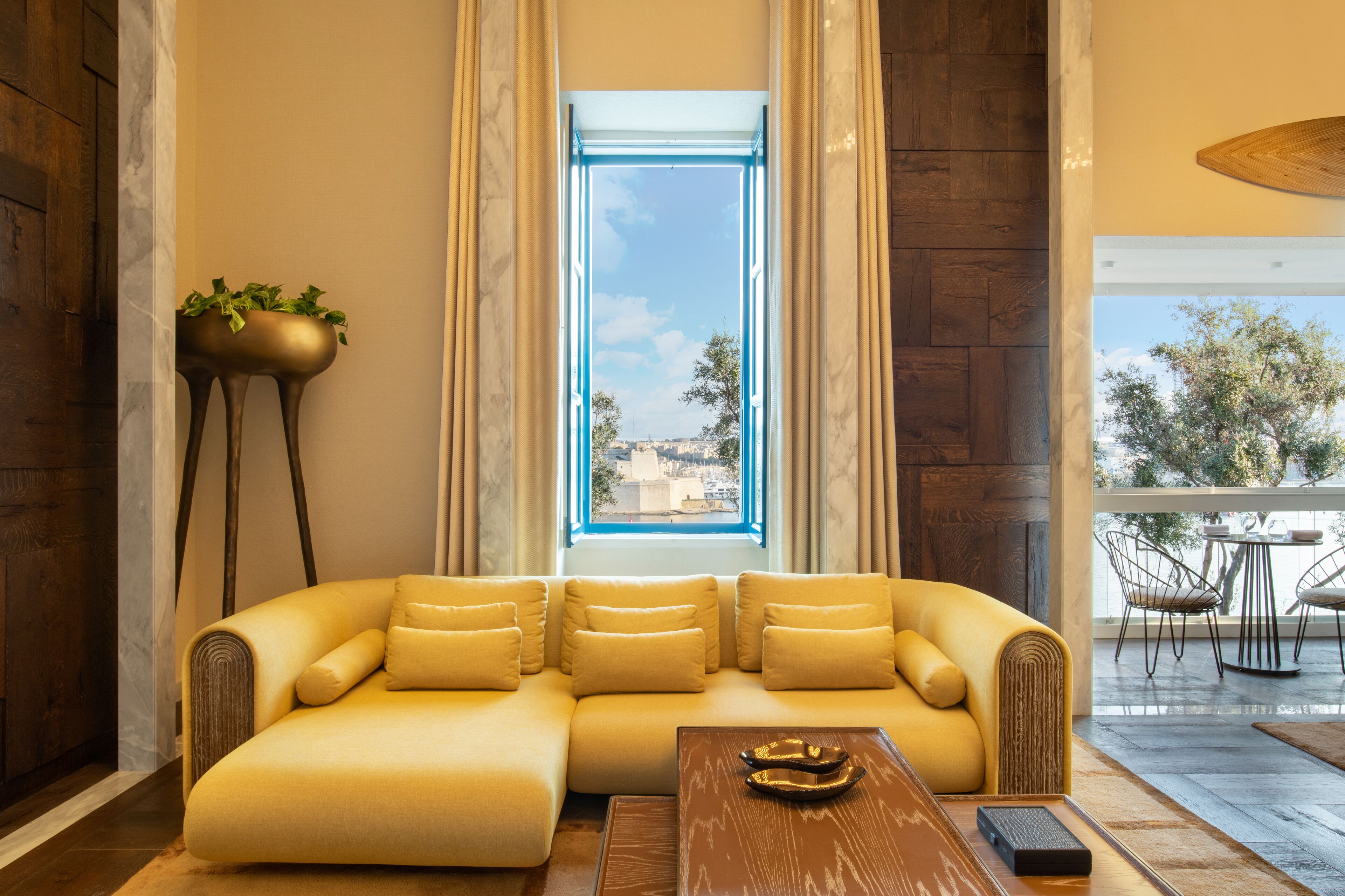 Uma sala de estar moderna com um sofá, uma mesa de centro e vista pela janela.