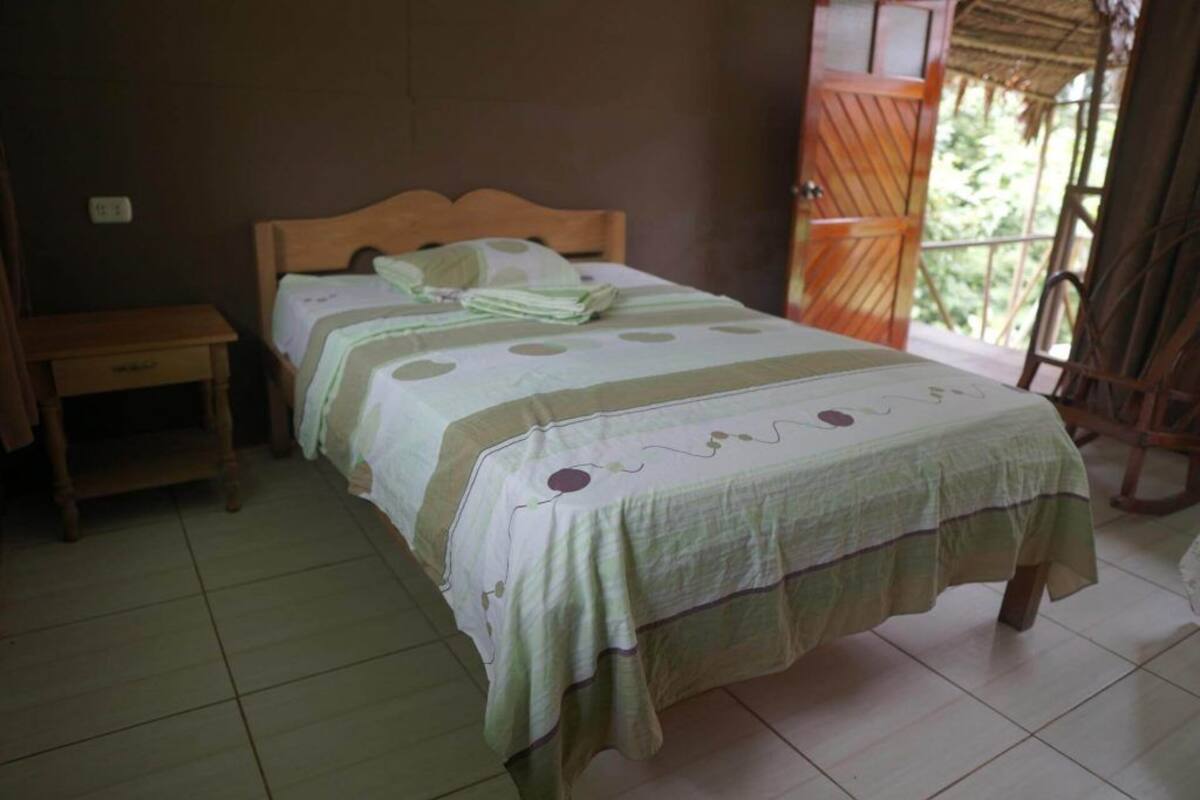 Uma cama de casal com cabeceira de madeira, mesa de cabeceira e guarda-roupa.