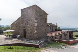 Um edifício de pedra com terraço e área de estar ao ar livre.