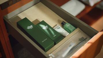 Uma gaveta com produtos de higiene pessoal organizados, incluindo uma caixa verde, lâmina de barbear e frasco de loção.