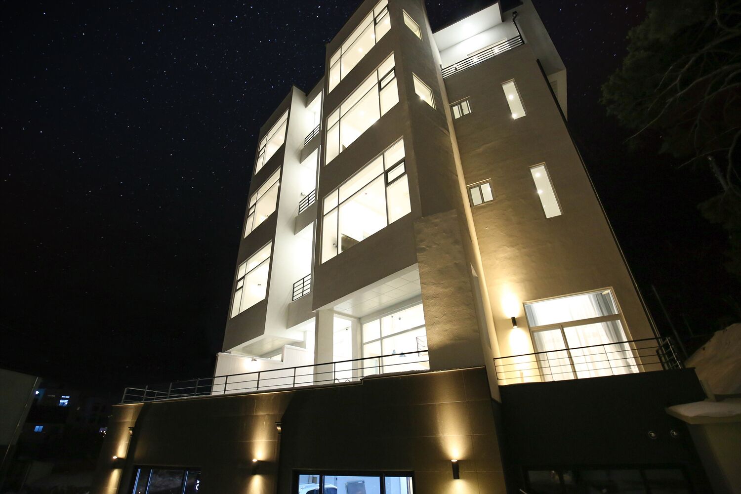Um edifício de vários andares com janelas e varandas iluminadas à noite.