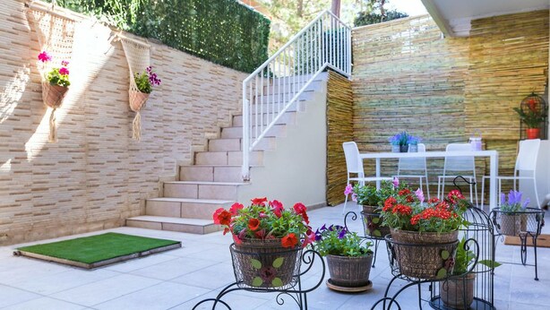 Uma área de pátio com escadaria, mobiliário para área externa e plantas em vasos.