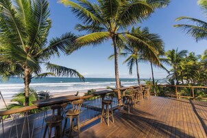 Na praia, areia branca, espreguiçadeiras, guarda-sóis 