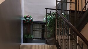 Uma escadaria com corrimão de metal e vasos de plantas no topo.
