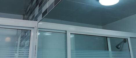 Um interior moderno com luminária no teto, corrimão de metal e janela com persianas.