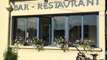 Um bar-restaurante com grandes janelas e caixas de flores.