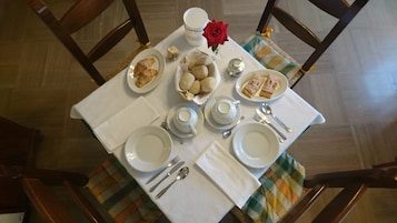 Uma mesa de jantar posta com pratos, tigelas, um bule e uma rosa.
