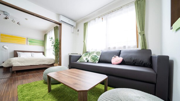 Quarto de hotel moderno com uma cama, um sofá, uma mesa de centro de madeira e um tapete verde.