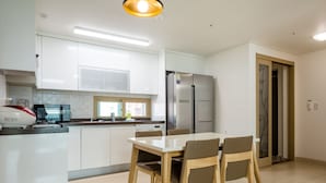 Uma cozinha moderna com armários brancos, uma geladeira de aço inoxidável e uma mesa de jantar com cadeiras.