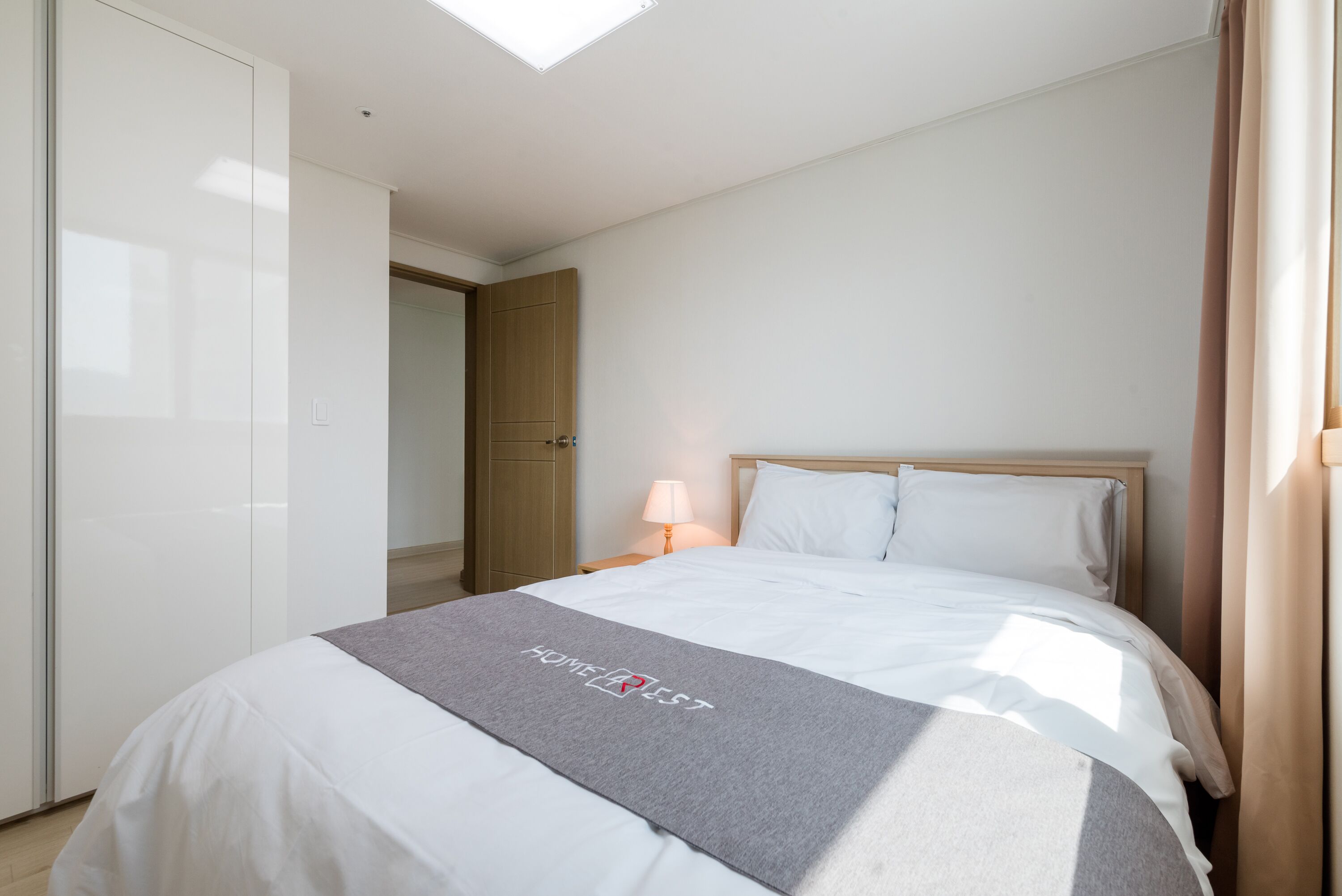 Quarto de hotel com uma cama, luminária de cabeceira e guarda-roupa.