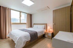 Quarto de hotel bem arrumado, com cama, mesa de cabeceira, abajur e guarda-roupa.