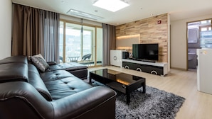 Uma sala de estar moderna com um sofá de couro, uma mesa de centro de vidro e uma televisão de tela plana.