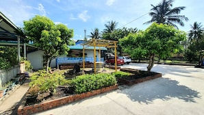 Área de jardim com pérgola, plantas em vasos e um pequeno elemento aquático.