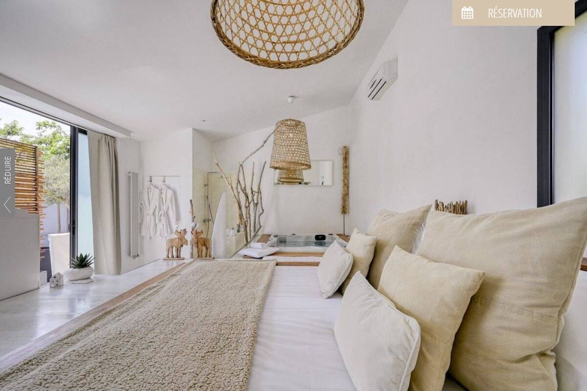 Quarto moderno com uma cama grande, luminária pendente e vista para o exterior.