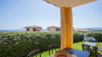 Um terraço com mesa e cadeiras, uma cesta de vime e vista para edifícios ao longe.