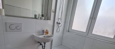 Uma casa de banho moderna com sanita, lavatório e chuveiro.