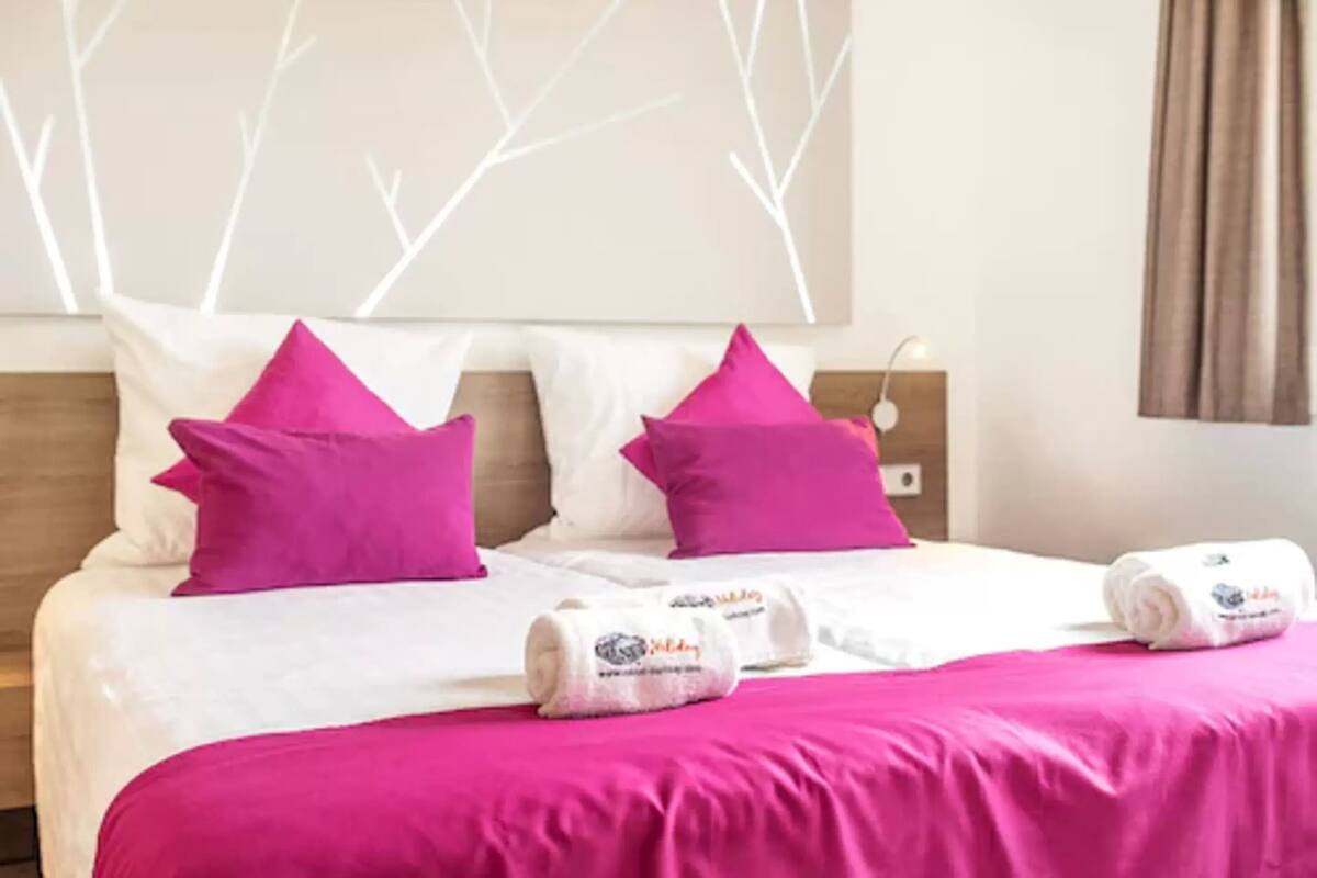 Quarto de hotel com uma cama, duas almofadas e duas toalhas.