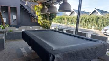 Uma área externa coberta com mesa de bilhar, escada e sinos pendurados.