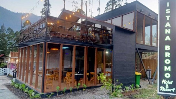 Um edifício moderno com fachada de vidro, deck de madeira e área de estar ao ar livre.