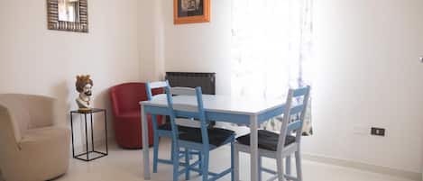 Uma área de refeições com uma mesa e cadeiras, um sofá, uma mesinha de apoio e um espelho na parede.