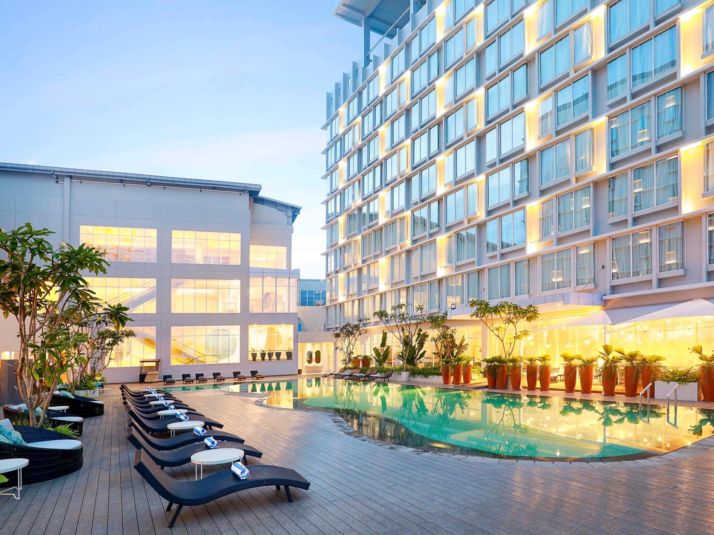 Um hotel com piscina no terraço, espreguiçadeiras e plantas em vasos.