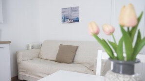 Uma sala de estar moderna com um sofá bege, uma mesa branca e um vaso com tulipas.