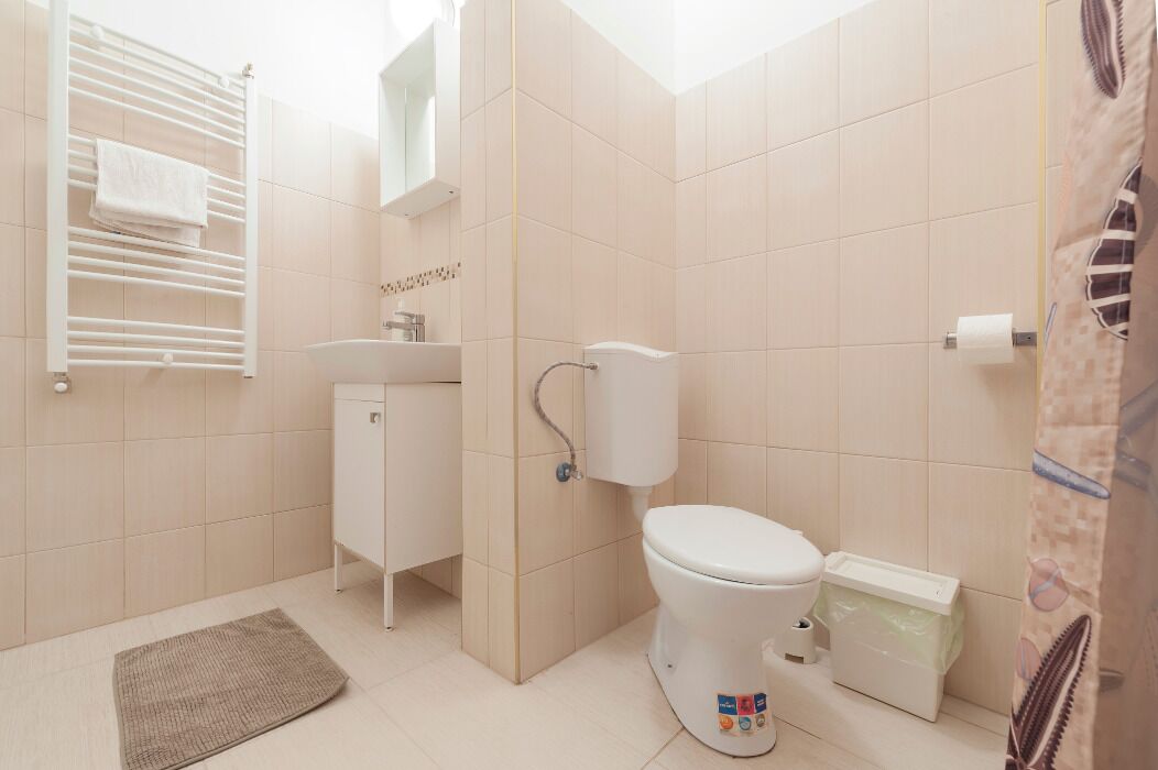 Casa de banho com sanita, lavatório e porta-toalhas.