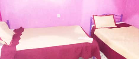 Quarto pequeno com uma cama de solteiro, parede roxa e chão branco.