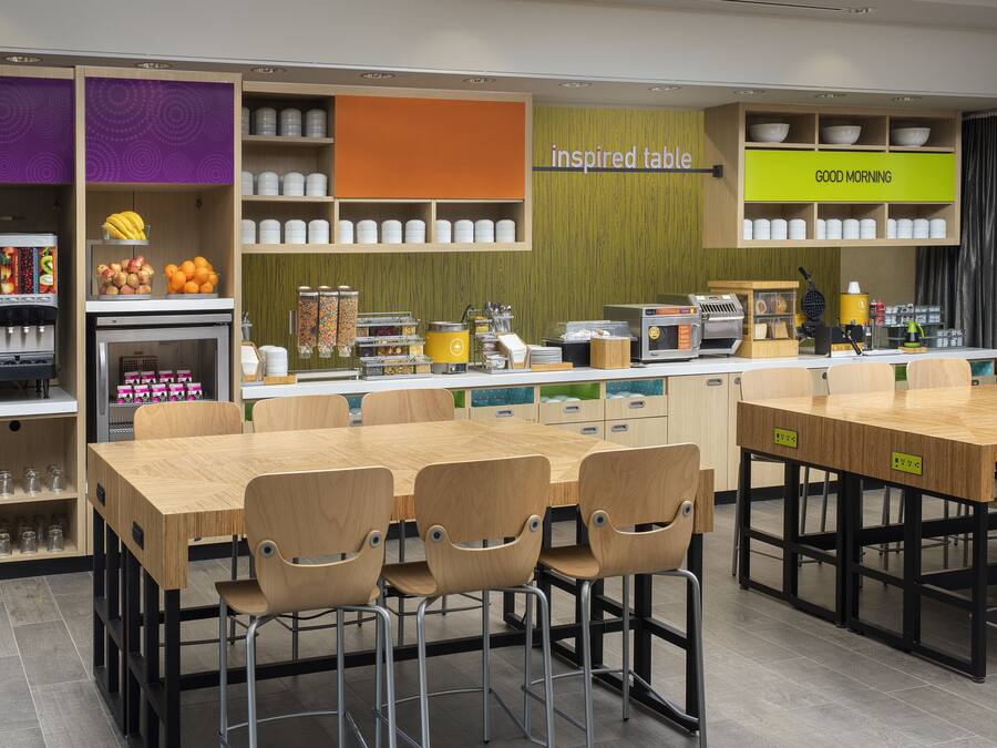Uma cozinha moderna com ilha central, banquetas de bar e diversos eletrodomésticos e espaços de armazenamento.